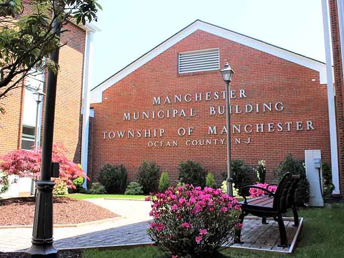 Manicured landscaping and blooming azaleas frame civic pride in brick, proving government buildings can actually look welcoming.