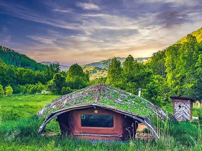 Sunrise paints the grass-covered roof in golden light, revealing how beautifully this structure harmonizes with its surroundings.