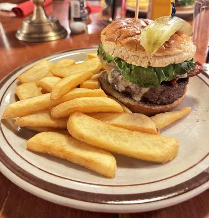 This burger stacked high with fresh toppings and golden fries represents everything right about American comfort food done properly.