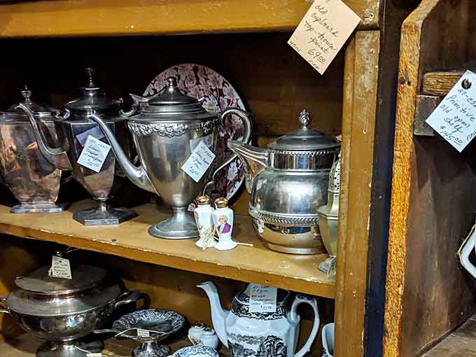 Ornate silver teapots and serving pieces gleam on wooden shelves, ready to host elegant gatherings like your great-aunt's Sunday socials.