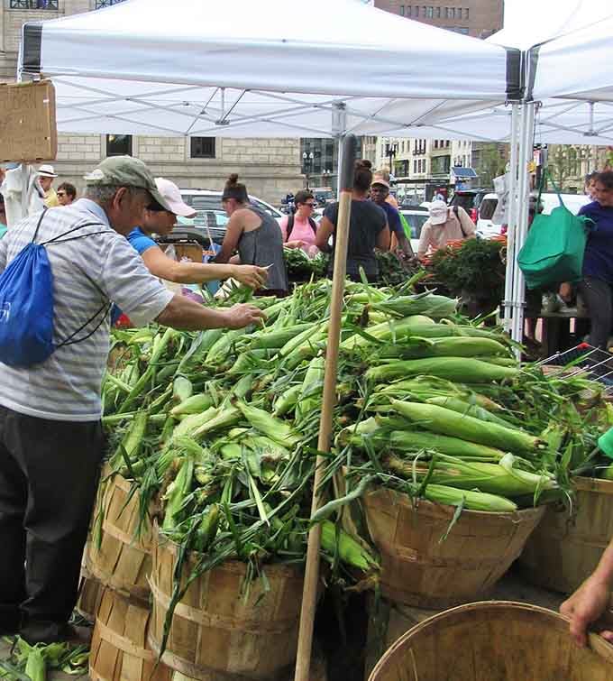 Corn piled high in bushel baskets, because New Englanders take their summer corn more seriously than playoff sports.