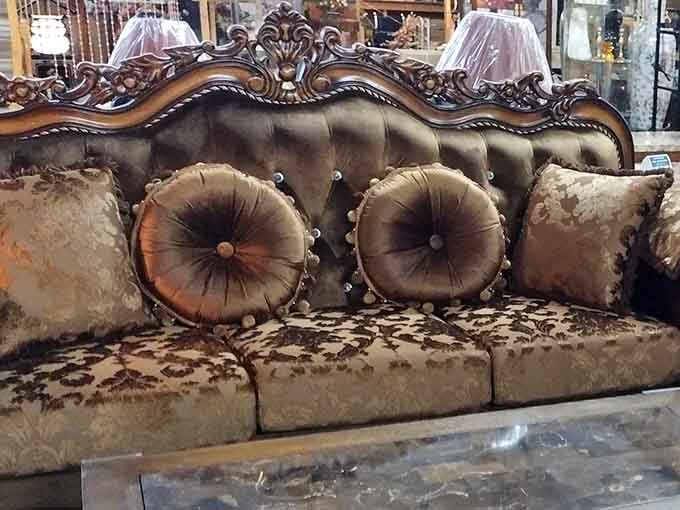 This ornate vintage sofa looks like it belongs in a palace, complete with tufted cushions and carved wood details.