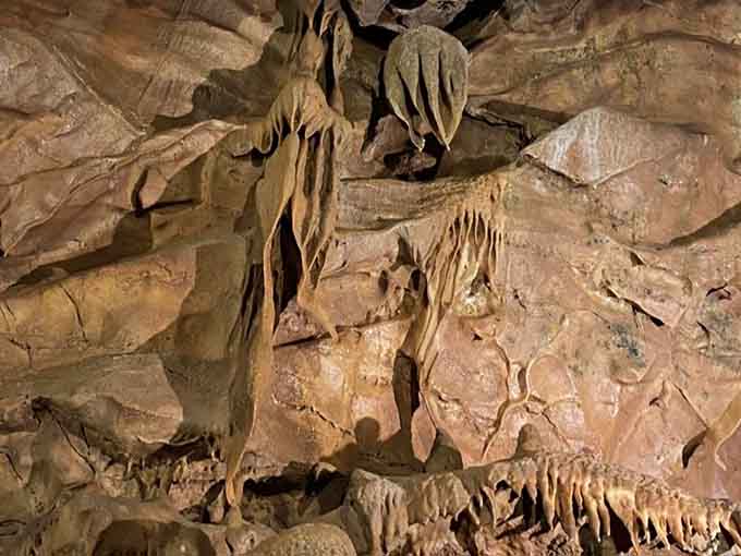 Intricate drapery formations hang delicately from the ceiling, showcasing the patient artistry of water and mineral deposits over time.