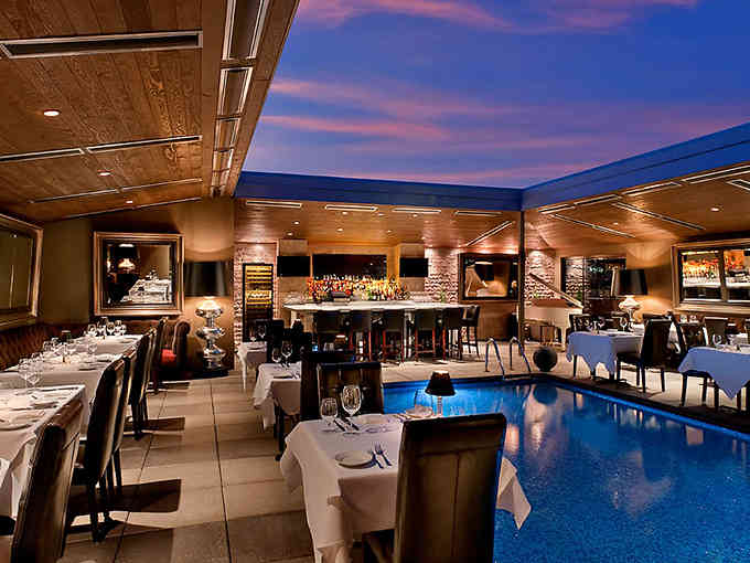 The dining room glows at twilight, with that stunning pool feature adding an unexpected touch of resort-style elegance to dinner.