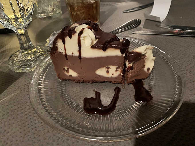 That towering slice of chocolate and vanilla pie with fudge drizzle is basically dessert doing victory laps.