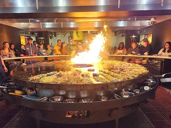 Flames leap dramatically from the circular grill as diners watch their custom creations come to life.