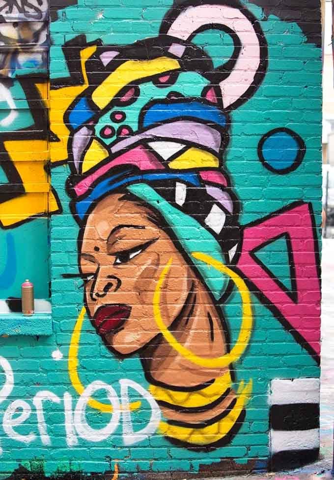 12. graffiti alley black woman Bold lines and bolder colors create a portrait that commands attention from every angle of the alley's expanse.