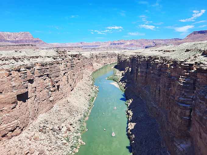 The Colorado River's turquoise waters contrast beautifully against rust-colored cliffs in this breathtaking aerial perspective view.