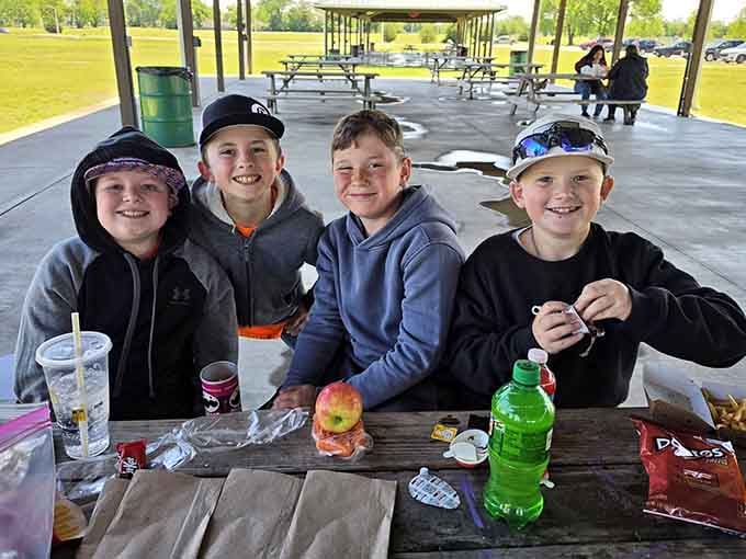 Four happy kids at a picnic table, surrounded by snacks. This is what a good park day looks like.