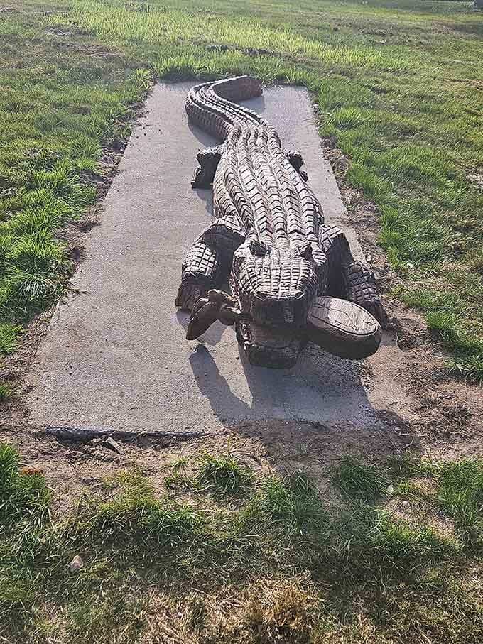 A full-sized wooden alligator lounging on the path like it's sunbathing in Florida instead of chilling in Michigan.