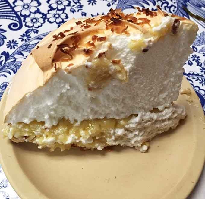 Coconut cream pie towering with meringue. Save room for dessert or regret it for days.