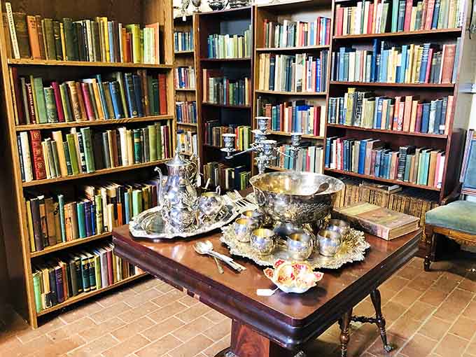 Shelves of vintage books paired with silver serving pieces because apparently literature and luxury go together perfectly.