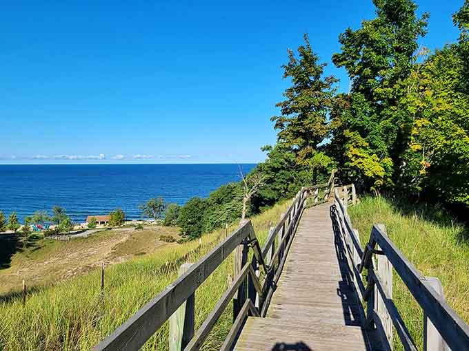 The boardwalk winds through dune grass toward the lake, building anticipation with every wooden plank beneath your feet.