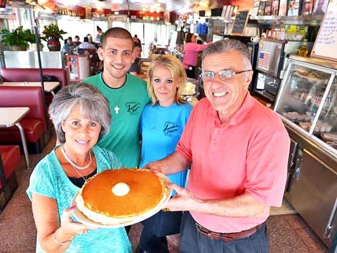 Happy customers holding proof that yes, pancakes really can be bigger than your entire head and then some.