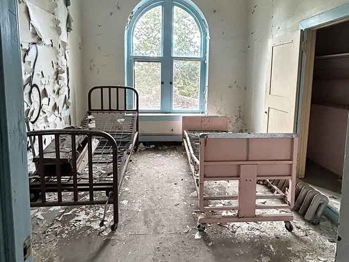 Metal bed frames and an arched window create a surprisingly serene scene, until you remember where you're standing exactly.