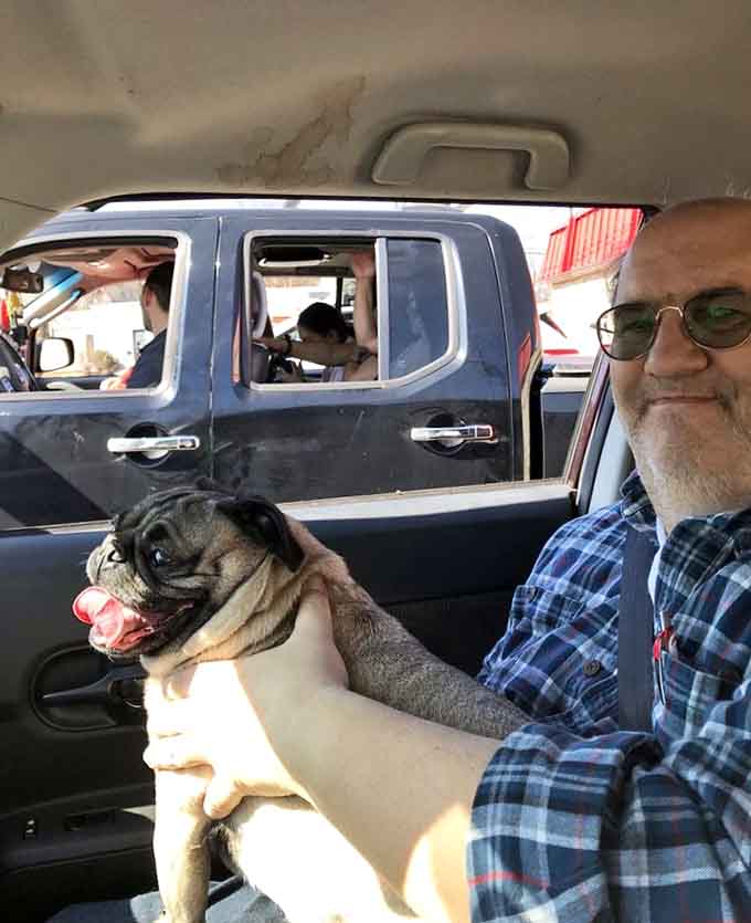 Happy customers and their equally happy pup enjoying the drive-in experience, because good food brings everyone together, even the furry ones.