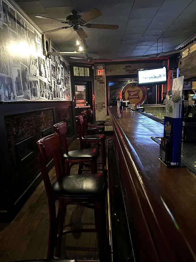 The long wooden bar stretches invitingly beneath vintage photographs, offering the perfect spot to ponder life over cold drinks.