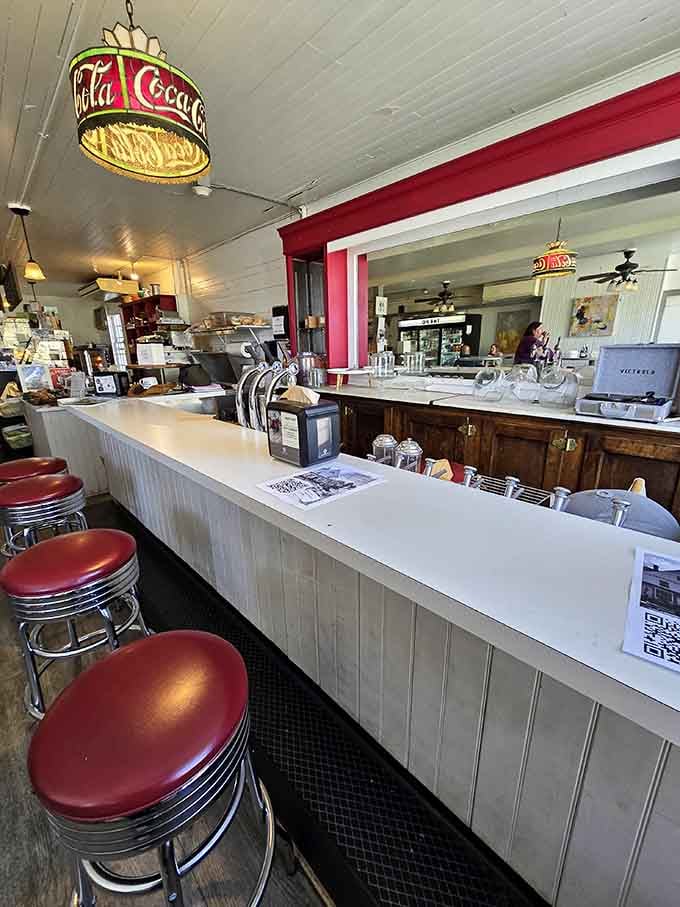 The vintage Coca-Cola light and classic counter setup create an atmosphere that feels both nostalgic and refreshingly unpretentious at once.