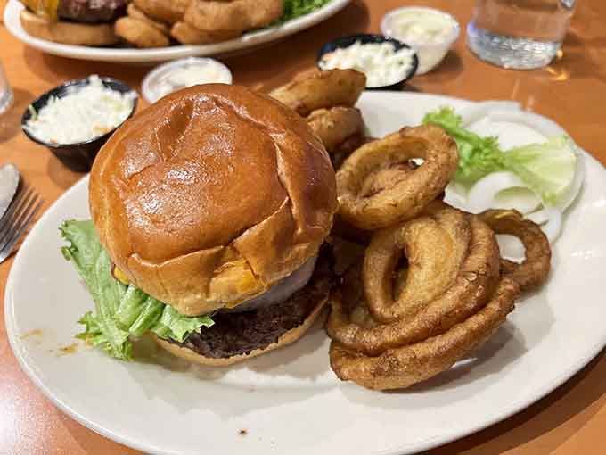 That burger sits confidently on its bun, knowing those onion rings beside it complete the picture of perfection.