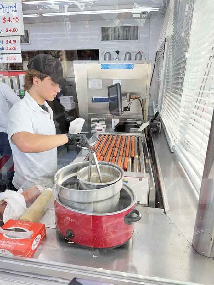 Behind the glass, a young cook tends to rows of franks with the focus of someone who takes their craft seriously.