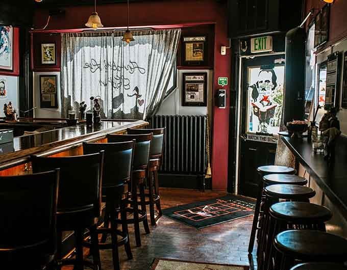 Curtains featuring Poe's silhouette frame the entryway, where literary ambiance meets neighborhood tavern warmth perfectly.