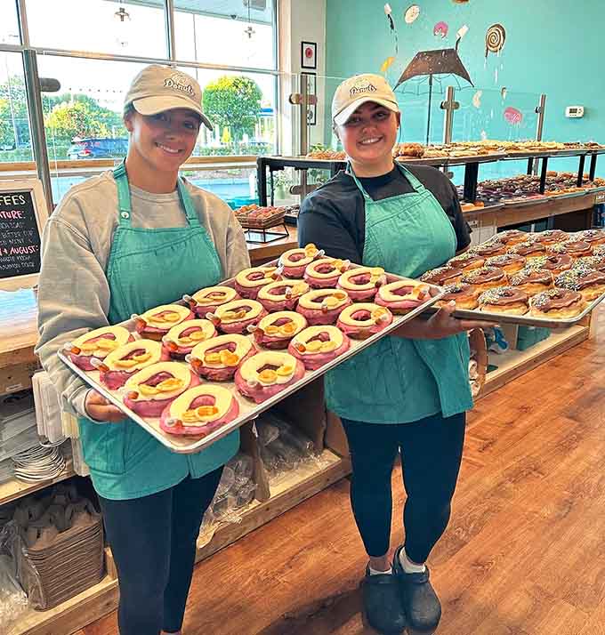 The smiling faces behind fresh donuts, bringing joy one tray at a time to grateful customers.