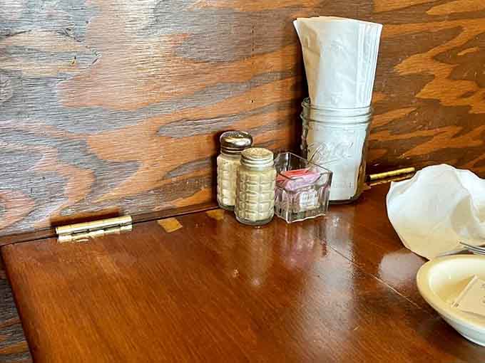 Salt, pepper, and napkins wait patiently on worn wooden tables that have witnessed decades of delicious decisions being made.