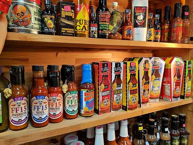 Hot sauce bottles parade across wooden shelves, ranging from mild to "call your cardiologist" levels of heat and flavor.