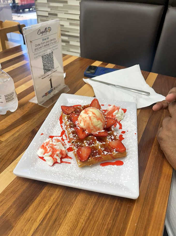 A Belgian waffle loaded with strawberries and vanilla ice cream, proving breakfast desserts are a legitimate food group.