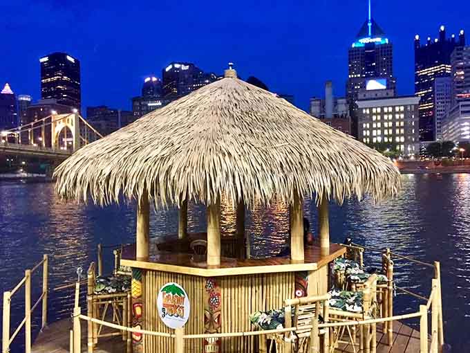 Pittsburgh's nighttime skyline provides the perfect backdrop for your illuminated floating tiki bar adventure under the stars.