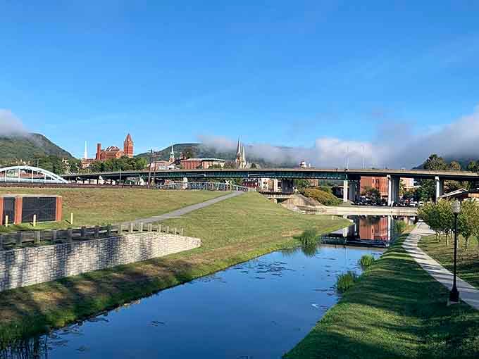 Morning mist rolls over the canal where bridges stack like a civil engineer's fever dream against mountain silhouettes.