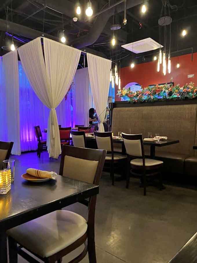 Elegant white curtains and purple mood lighting transform this dining space into something special without feeling stuffy or pretentious.