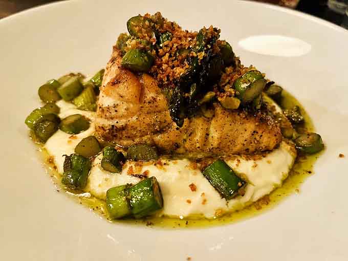 Perfectly cooked salmon nestled on creamy polenta with crispy breadcrumbs, showing seafood gets serious respect here too.