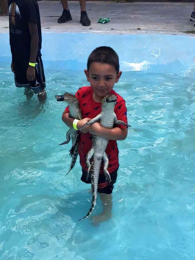 This kid's hugging baby alligators in a pool, living every reptile-loving child's absolute wildest dream come true.