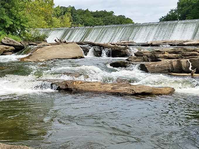 Watch the water flow over the rocks and dam, offering a serene escape into the natural beauty of the area.