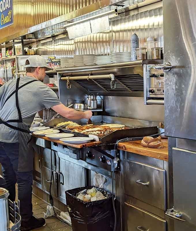 Watching breakfast come together on the griddle, where skilled hands turn simple ingredients into morning magic daily.
