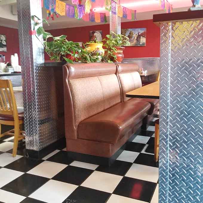 Comfortable booth seating with plants and decorative touches makes every meal feel like a mini celebration.
