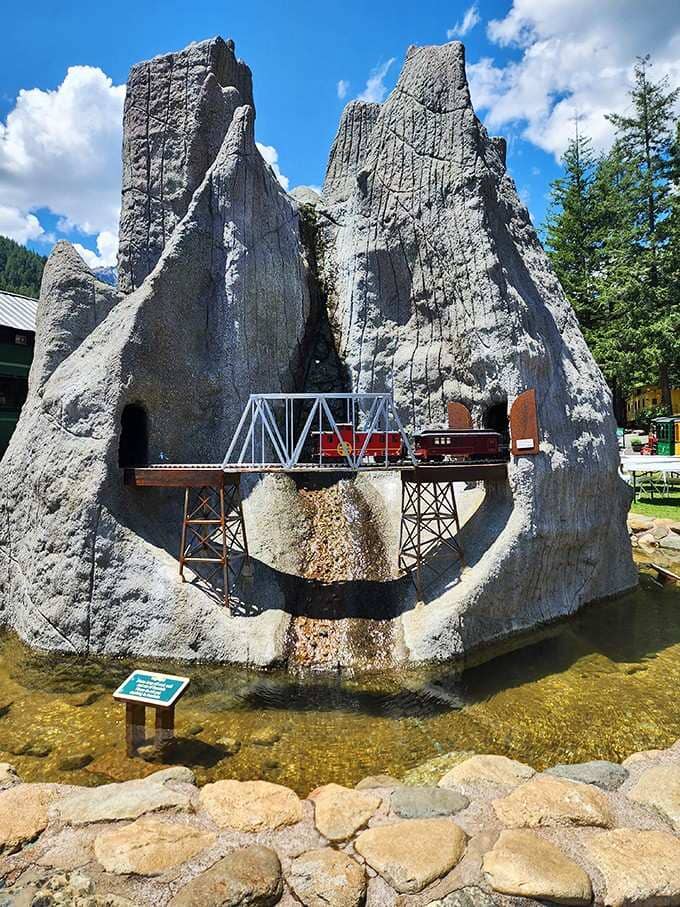 That miniature train crossing a sculpted rock formation shows someone's dedication to railroad whimsy taken seriously.
