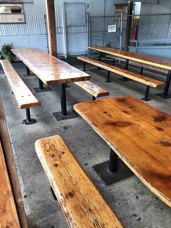 Wooden picnic tables under corrugated metal, the perfect setup for eating without fancy dining room pretense.