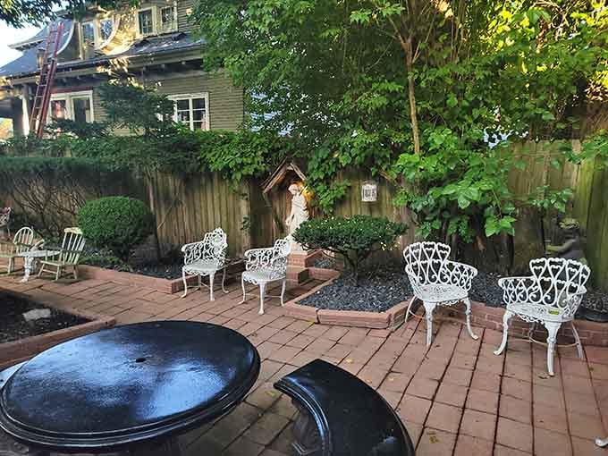 White wrought iron furniture scattered across brick pavers makes outdoor dining feel like a secret garden escape.