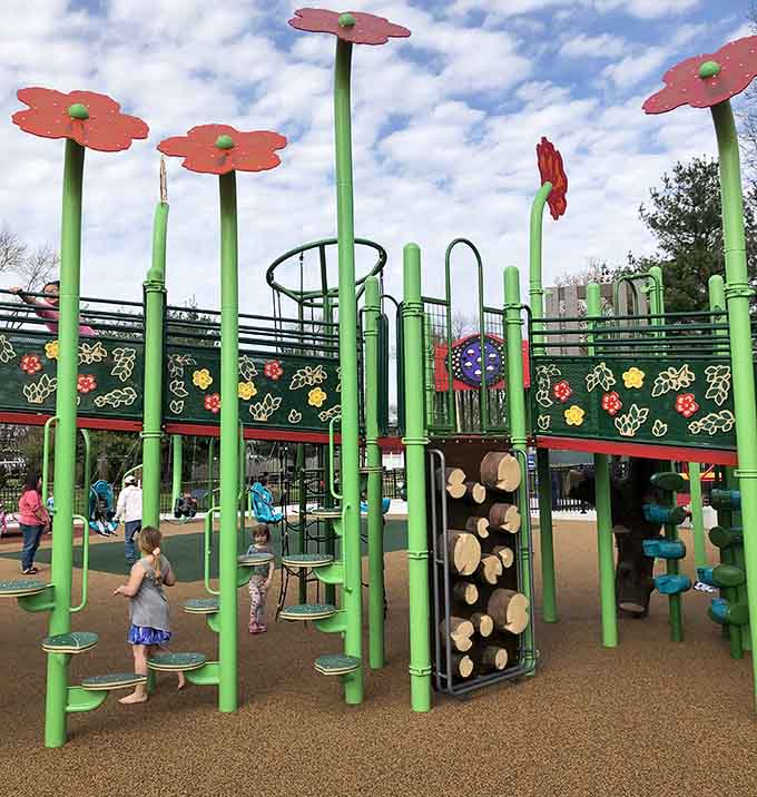 Climbing structures with flowers blooming above create a garden atmosphere where physical challenges feel like pure play and exploration.