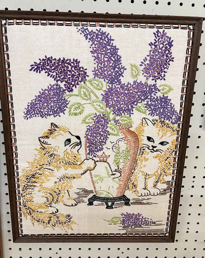 Embroidered kittens admiring flowers, because your grandmother's generation understood the importance of whimsical wall art perfectly.
