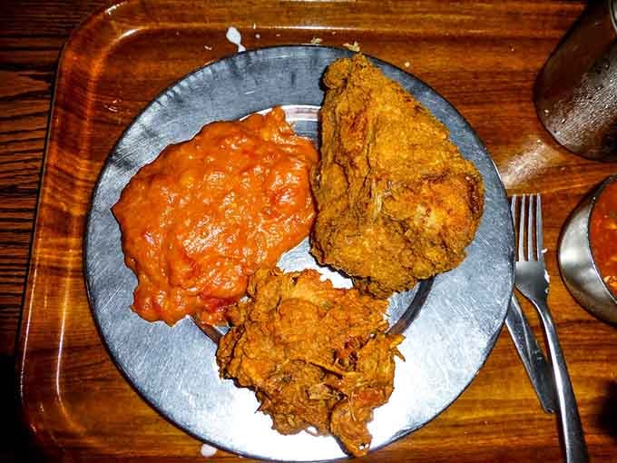 Fried chicken and pulled pork sharing a plate with stewed tomatoes like the holy trinity of Southern cooking.