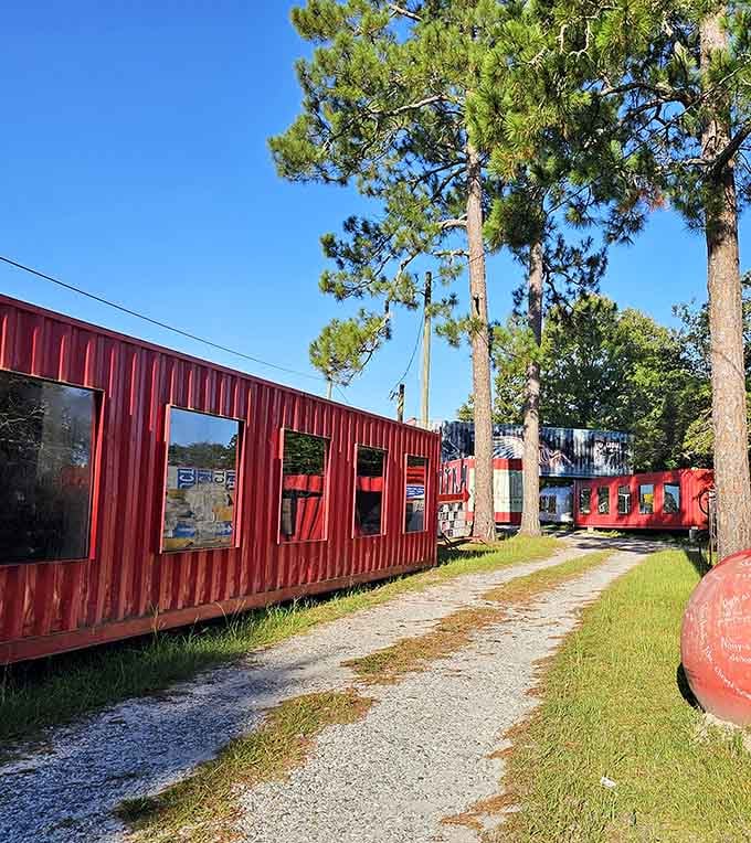 Red corrugated structures line the gravel path like a carnival midway designed by an outsider artist with serious vision and style.