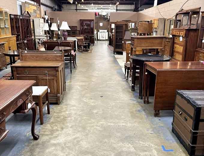 Furniture stretches down the aisle like a wooden forest, each piece waiting for someone to appreciate its craftsmanship.