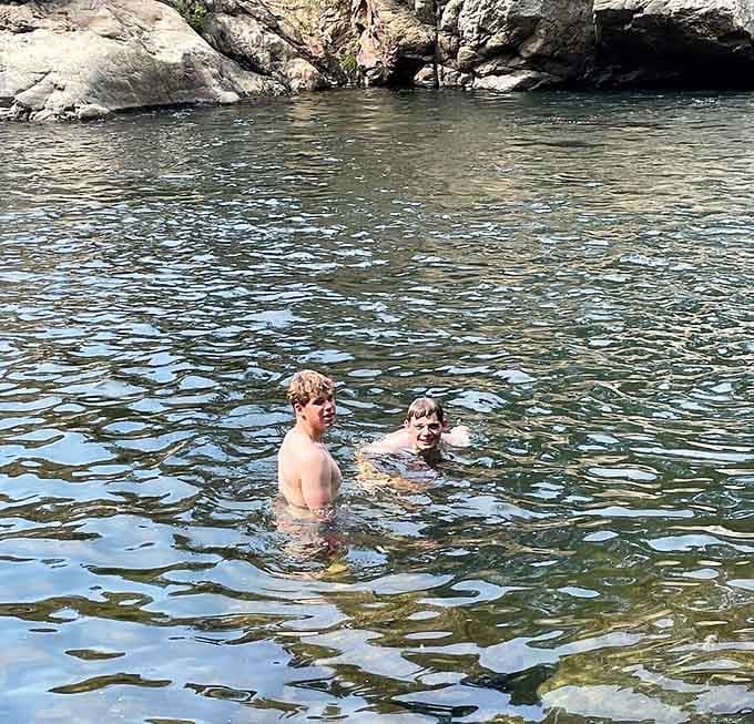 Two friends enjoying cold mountain water on a warm day, living their best life without Wi-Fi or worries.