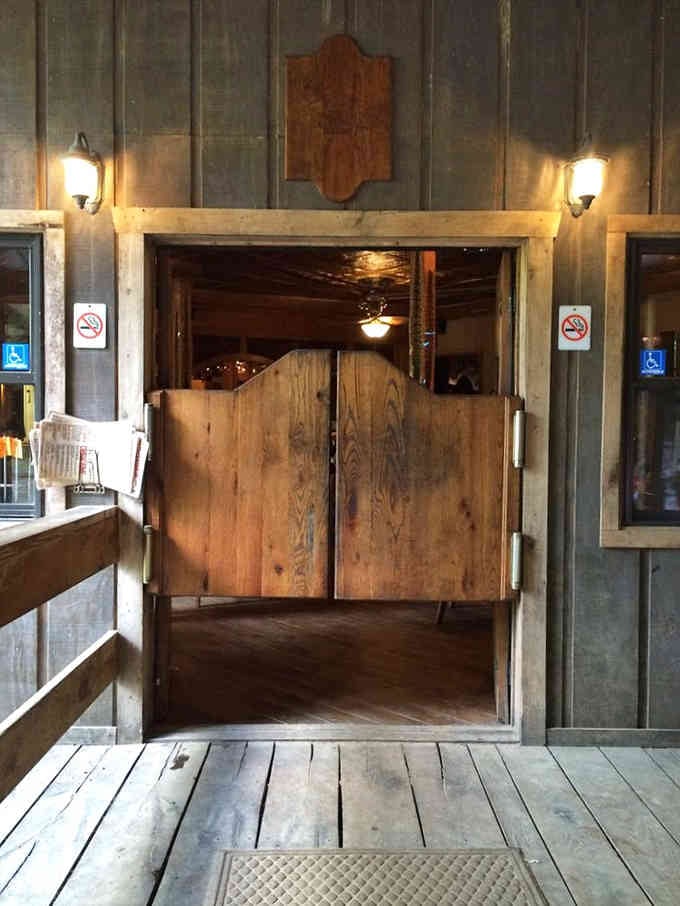 Swinging saloon doors beckon you inside where rustic wood meets ancient stone in the most unexpected restaurant entrance you'll ever walk through.