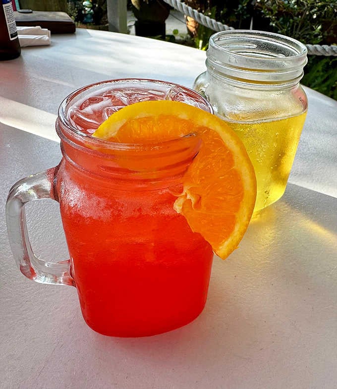 Colorful drinks in mason jars with orange slices, making hydration look like a tropical vacation in a glass.