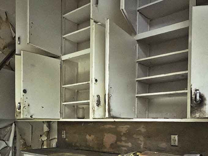 Empty cabinets with doors hanging open look like they're screaming silently about all the medical supplies they once held.