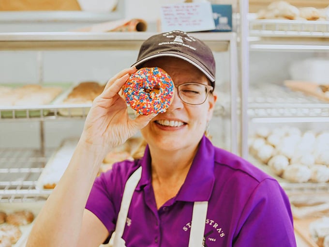 That donut-framed smile says it all: working here beats working anywhere else, and the perks are delicious.